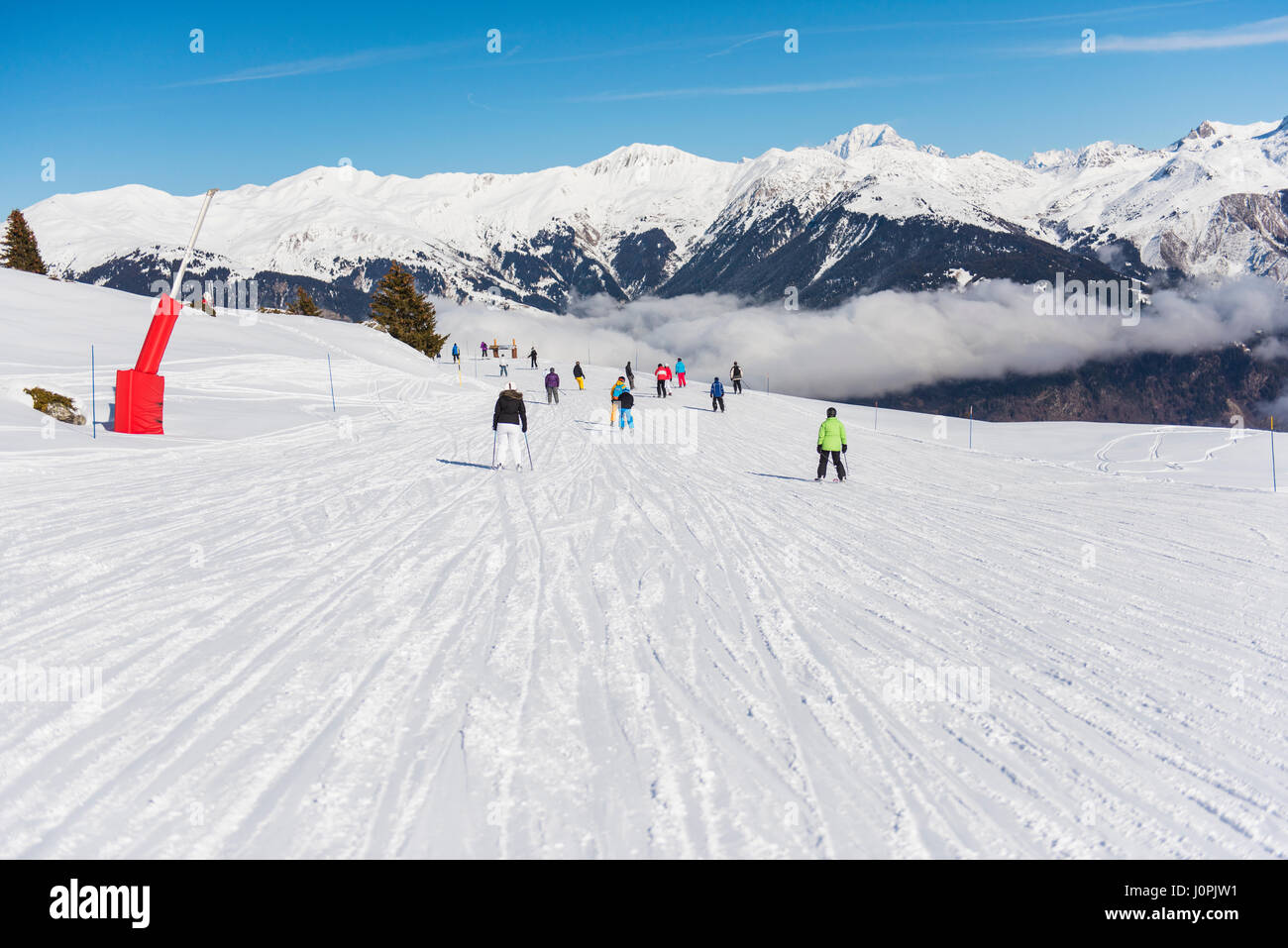 Skiers on a ski slope piste in winter alpine mountain resort Stock ...