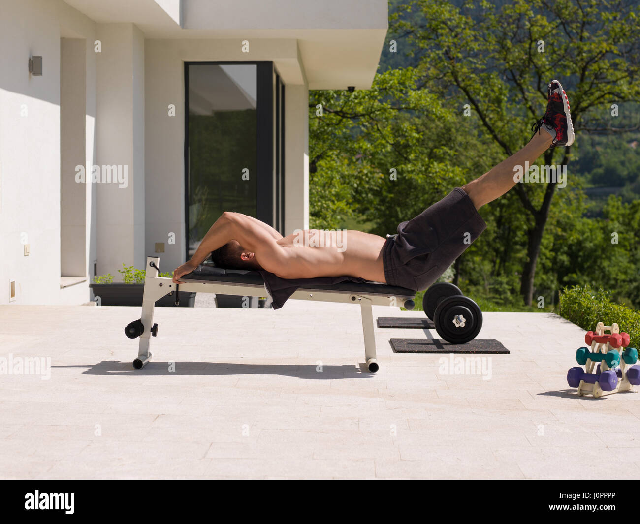 young handsome man doing morning exercises in front of his luxury home ...