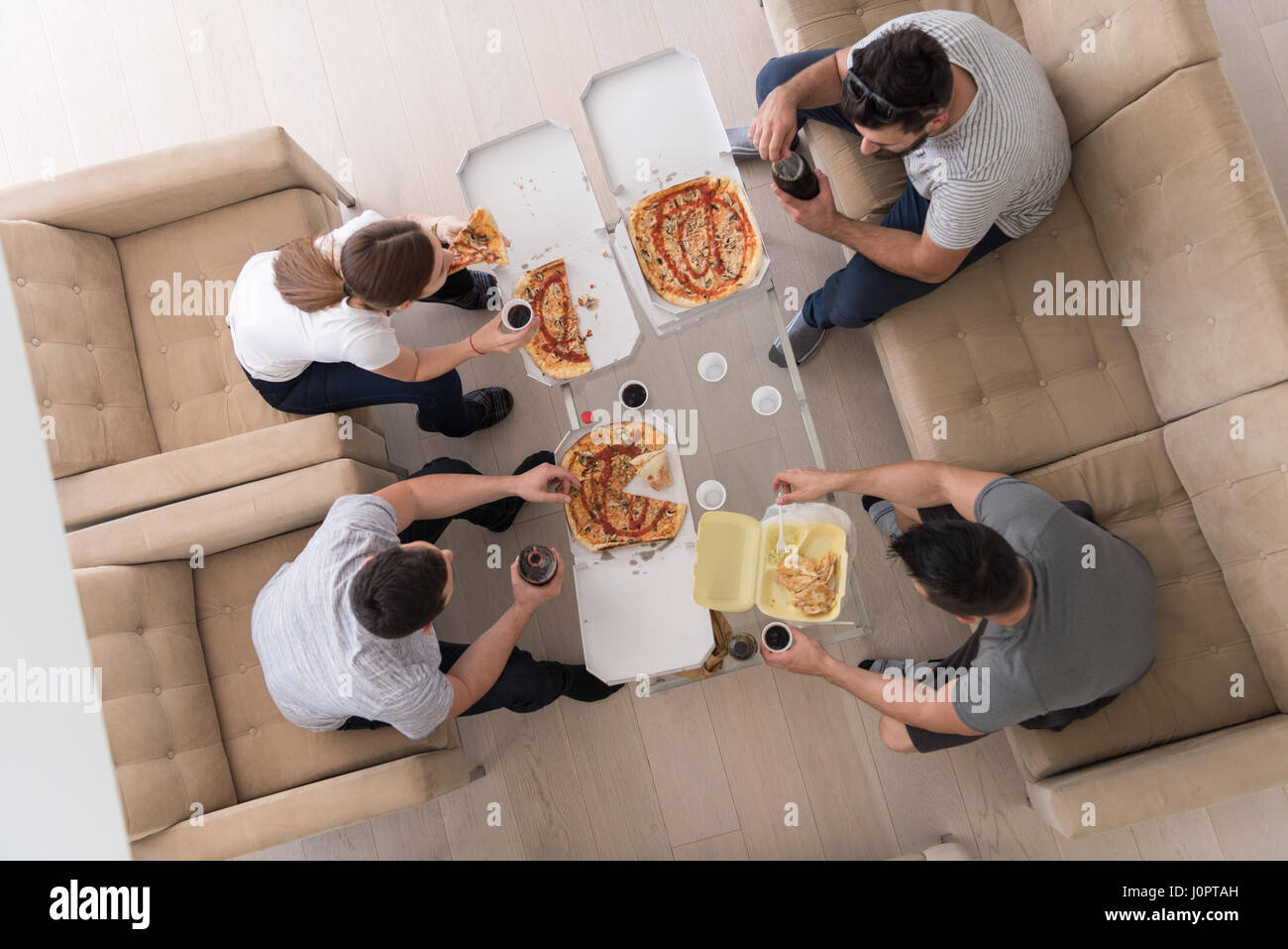 a group of young people cheerfully spending time while eating pizza in ...