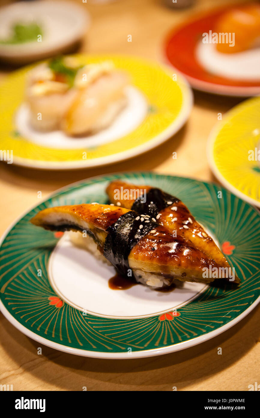 Close up of grilled unagi freshwater eel on nigiri sushi rice served with BBQ sauce and ...