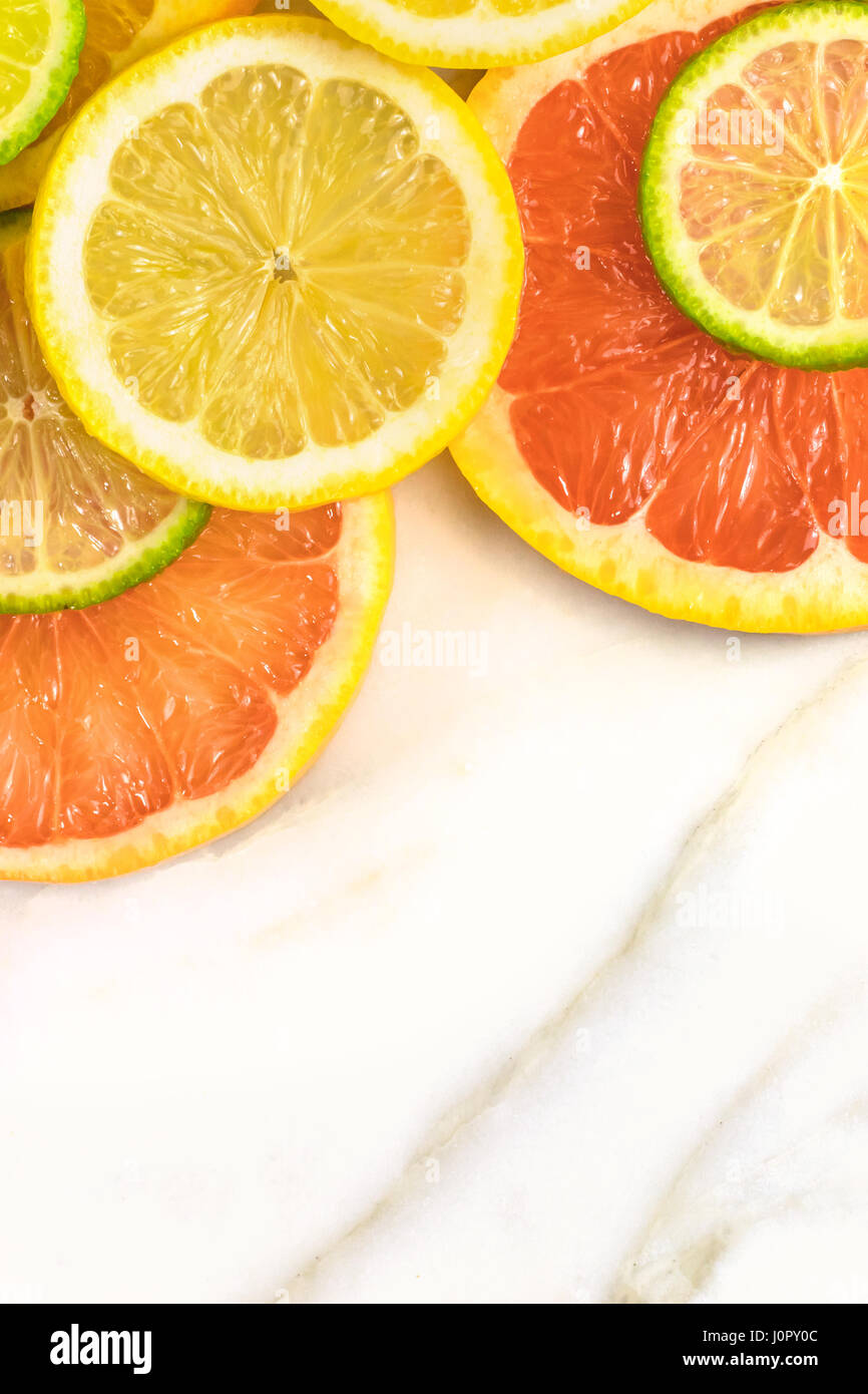 Vibrant juicy citrus fruits on a white marble texture with copy space ...