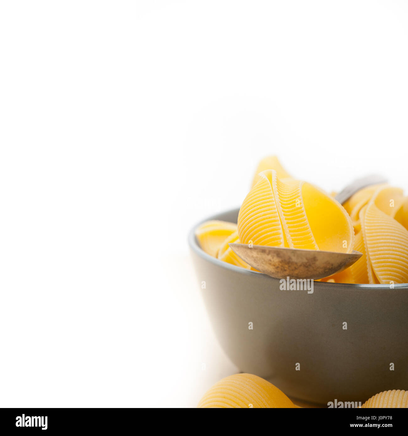 raw Italian snail lumaconi pasta on a blue bowl over rustic table macro ...