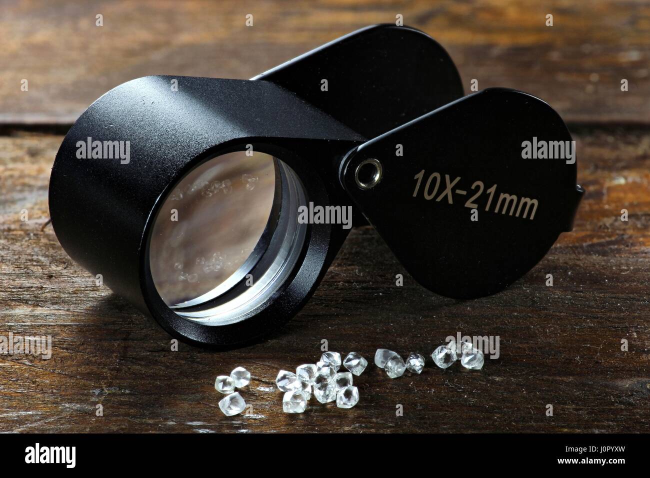 rough diamonds with folding magnifier on wooden background Stock Photo ...