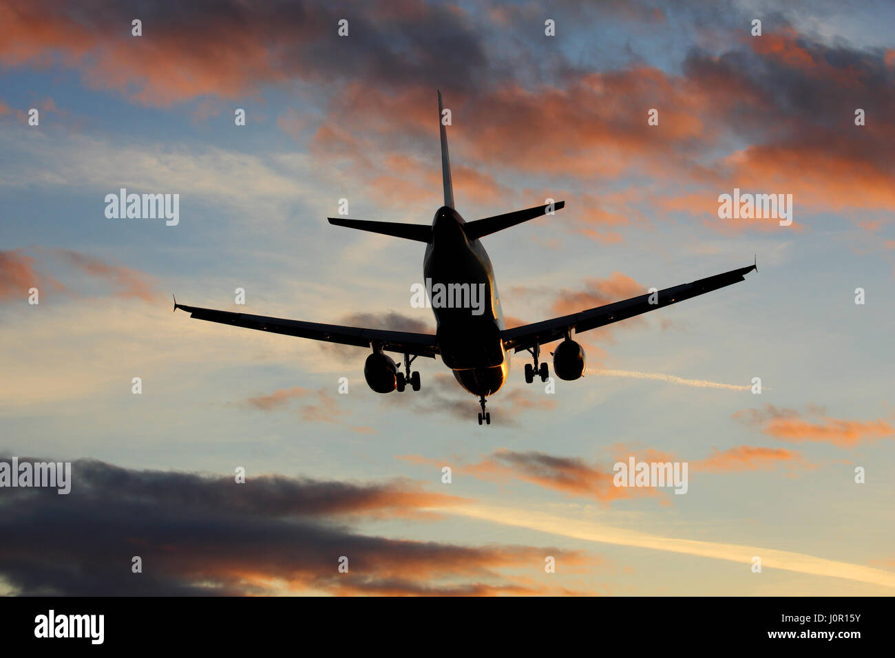 Large airliner landing at London Heathrow airport silhouetted against a ...