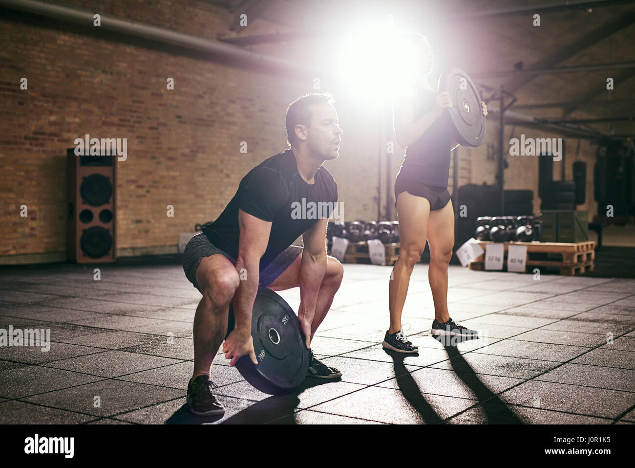Sportive man and woman doing exercise with weight discs from squat in ...
