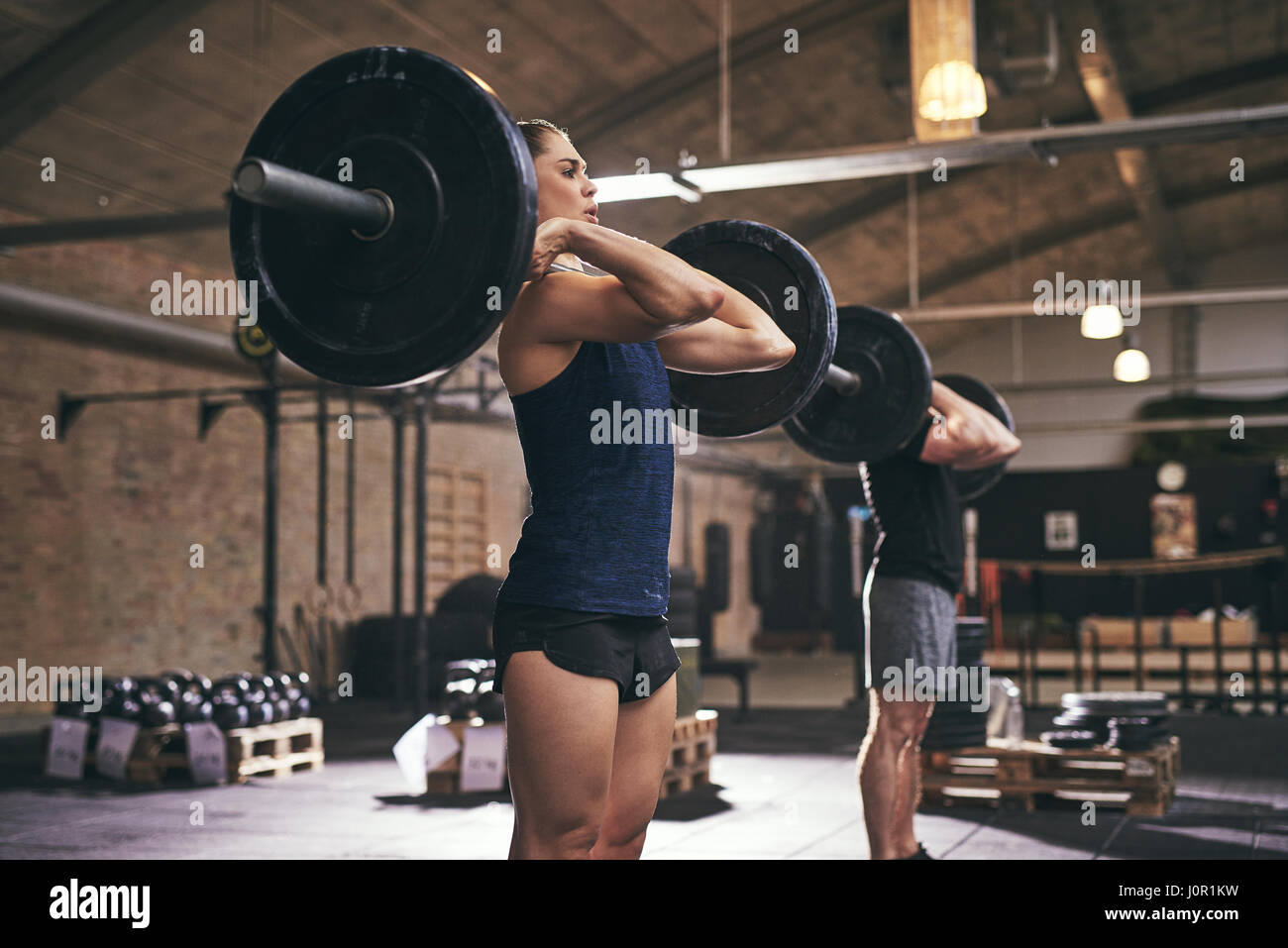 Fit people holding barbells on their shoulders while exercising ...