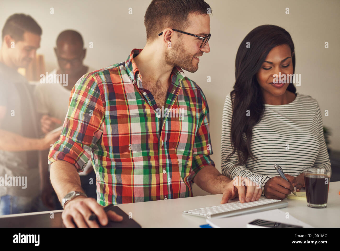 Cheerful young creative people taking notes while cooperating in the ...