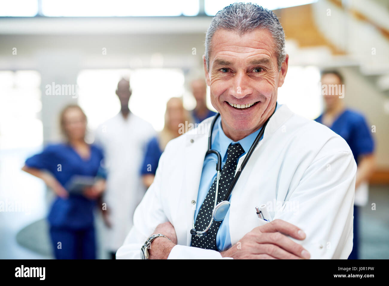 Portrait of cheerful doctor in a hospital standing with arms crossed ...