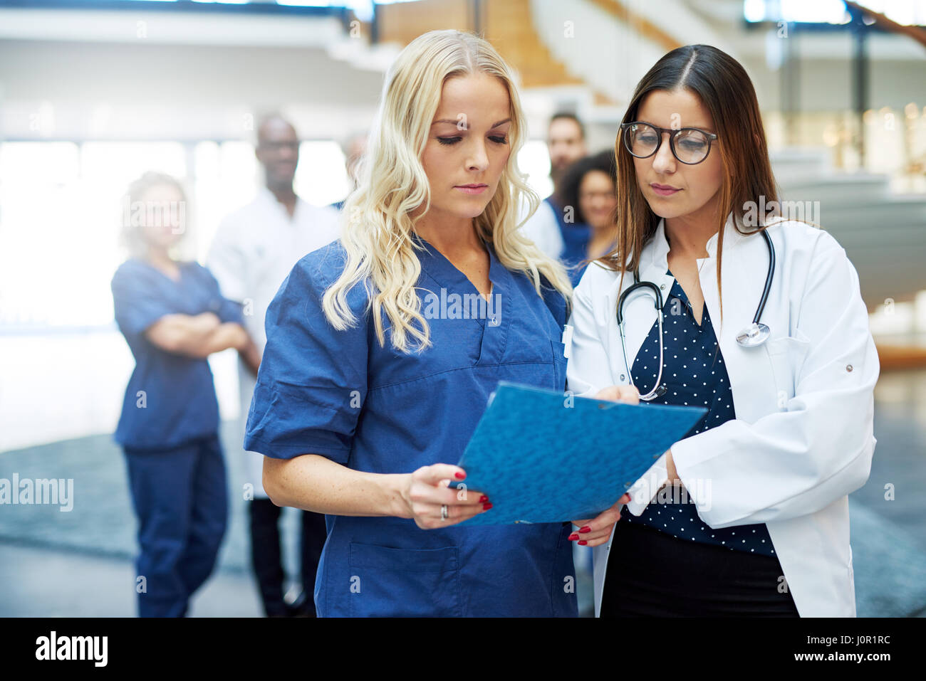 Two young female medics standing in the clinic and looking through the ...