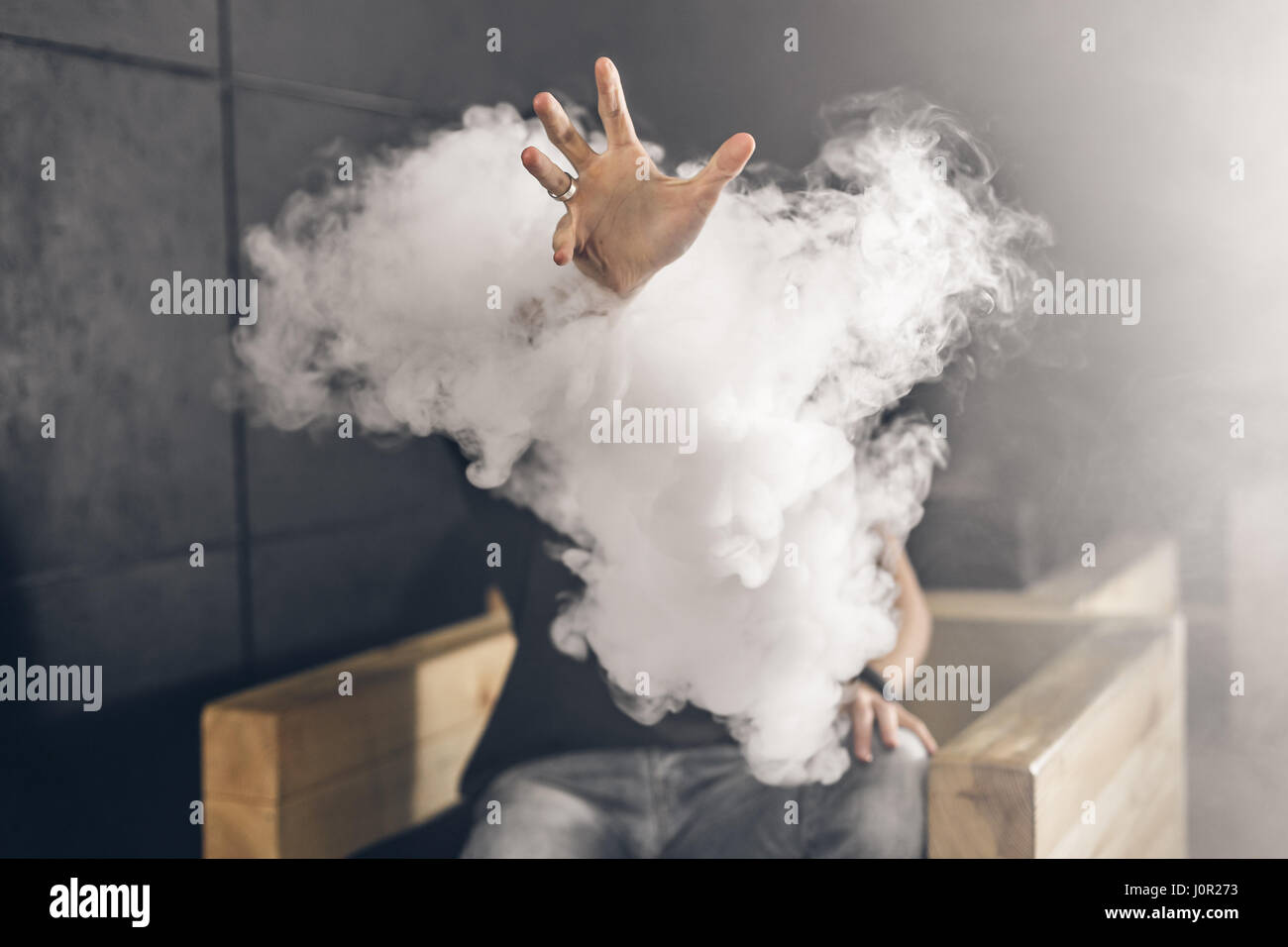 Smoke sticks out of the smoke. Man is vaping in the dark room Stock ...