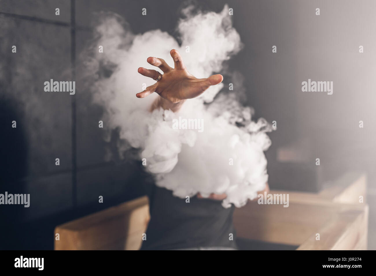 Smoke sticks out of the smoke. Man is vaping in the dark room Stock ...