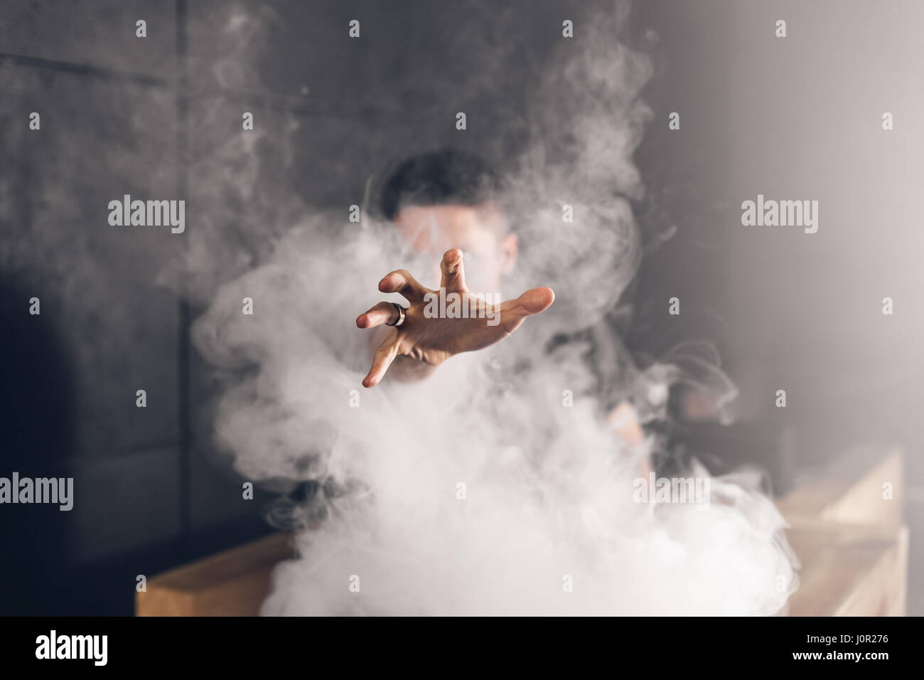 Smoke sticks out of the smoke. Man is vaping in the dark room Stock ...