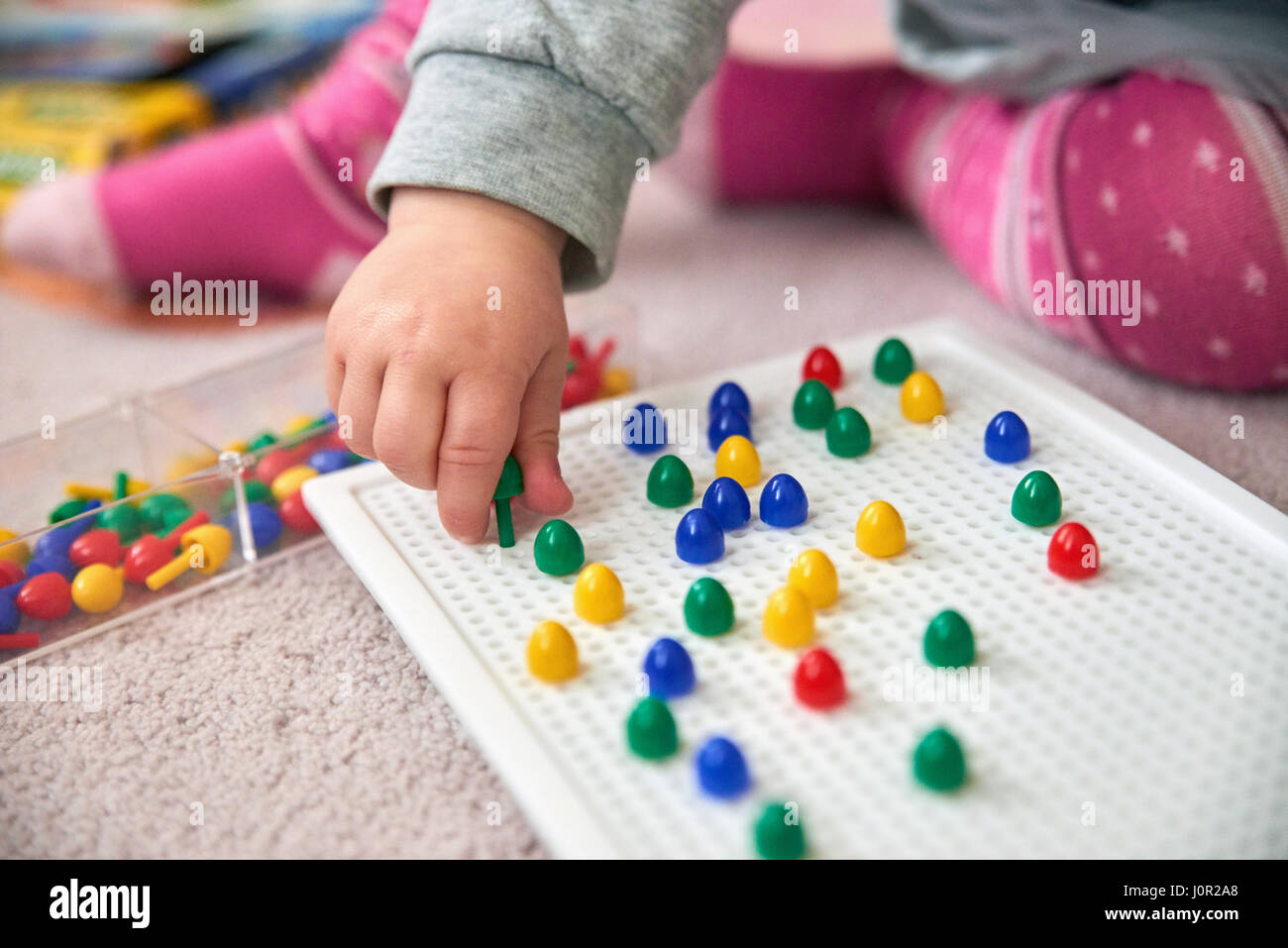 toddler plays with colorful pins Stock Photo - Alamy