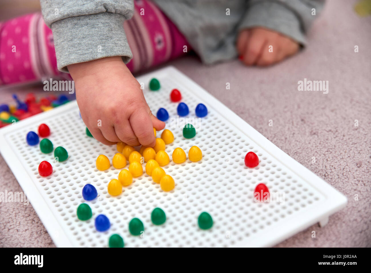 toddler plays with colorful pins Stock Photo - Alamy