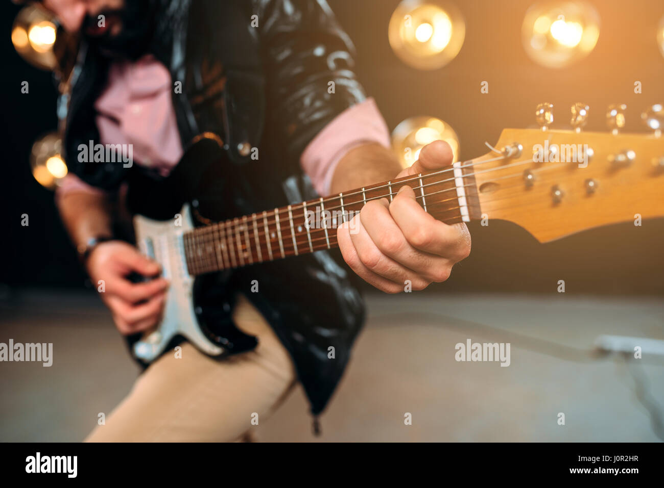 Male guitarist hands performing music on the stage with the decorations ...