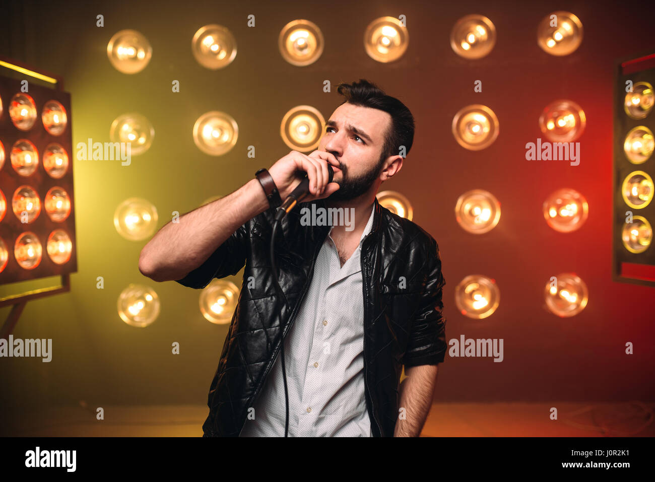 Brutal bearded singer with microphone on the stage with the decorations ...