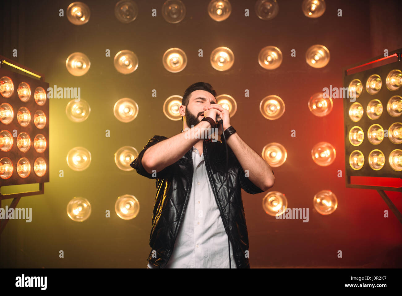 Brutal bearded singer with microphone on the stage with the decorations ...