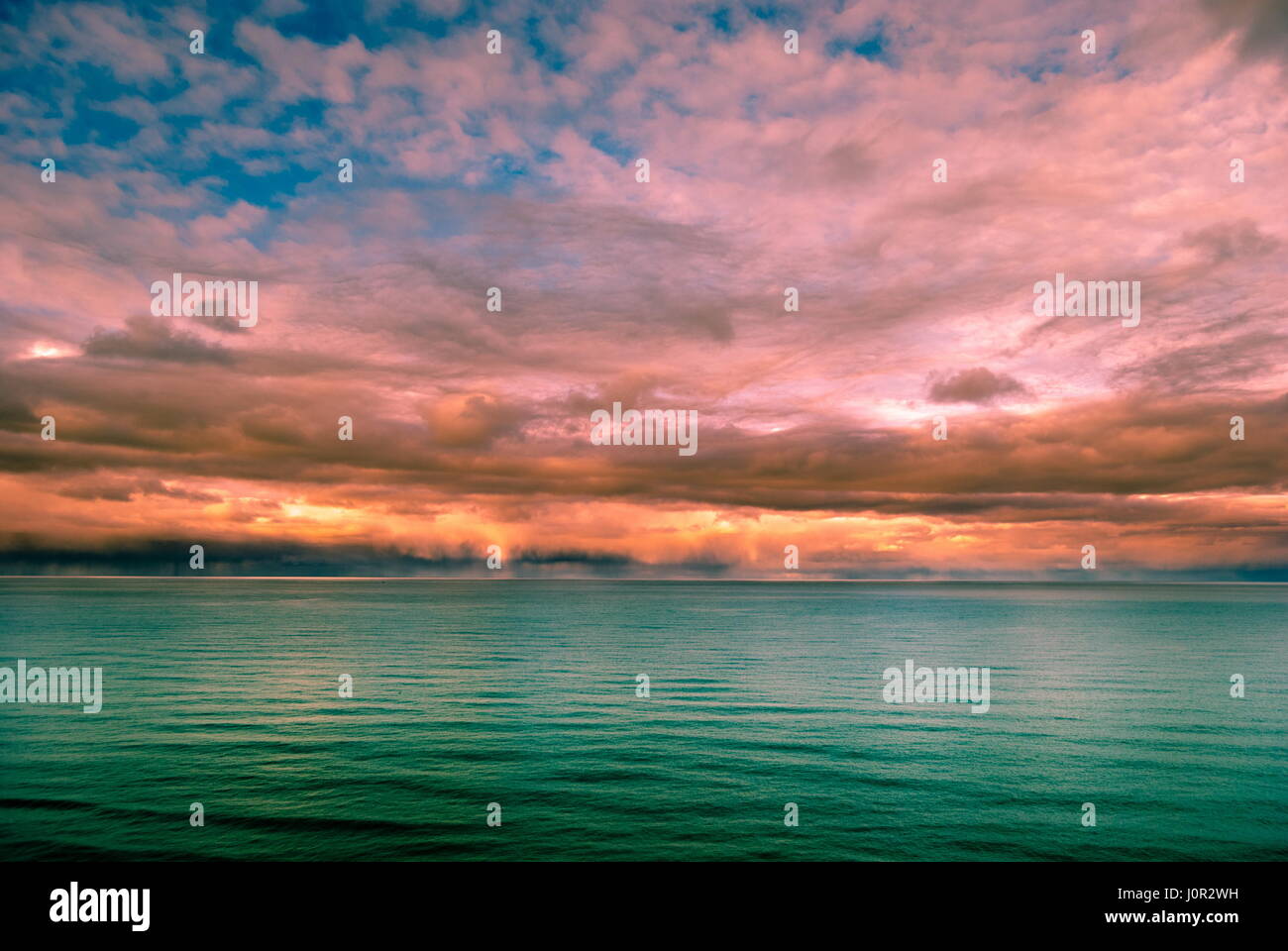 Multicolored surreal sunset view of a rocky coastline Stock Photo - Alamy