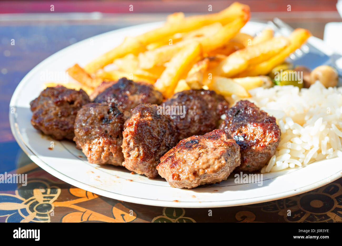 Lamb kofta with rice, french fries, olives on white plate in Moroccan ...