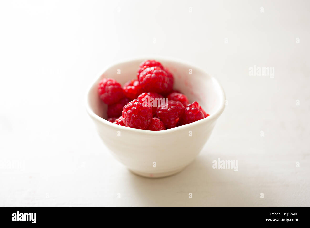Raspberries in white bowl isolated on white background Stock Photo - Alamy