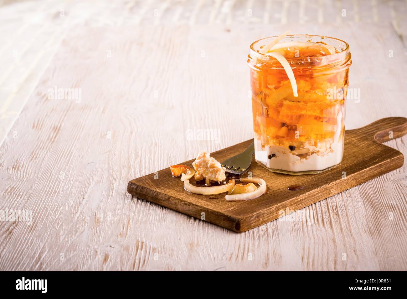 Horizontal photo of pickled cheese in glass jar with single bite on top ...