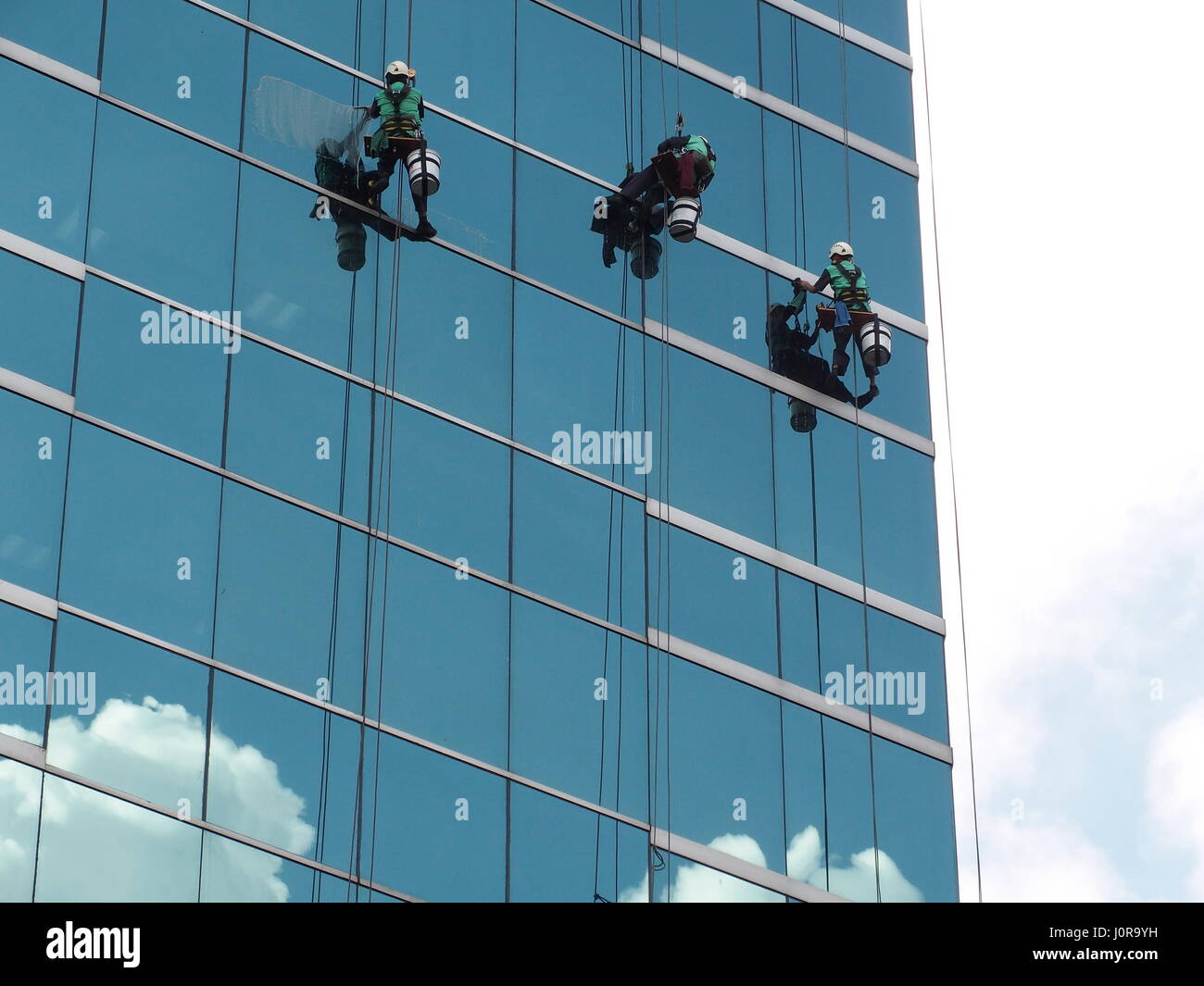 Men cleaning glass building by rope access at height Stock Photo - Alamy