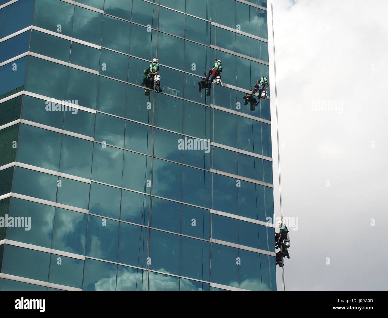 cleaning glass building by rope access Stock Photo - Alamy