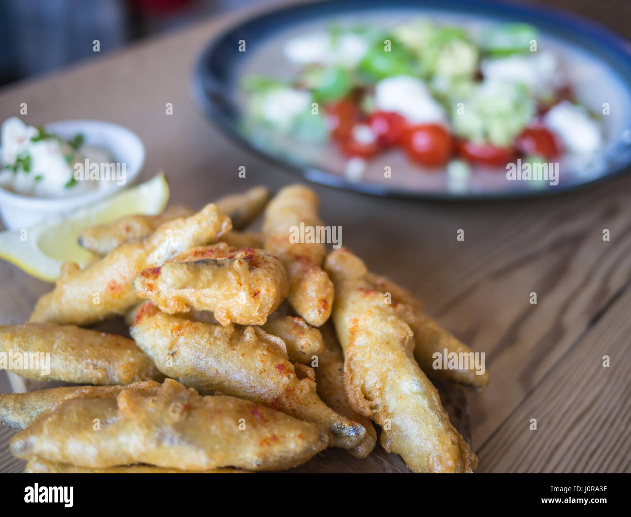 Deep fried whitebait, sprats in batter served with a lemon slice and ...