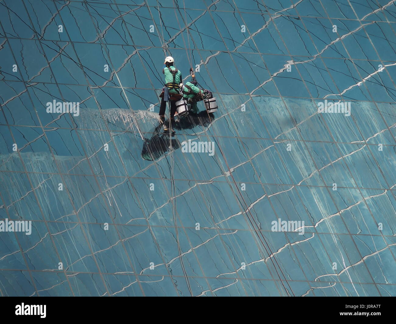 men cleaning glass building by rope access Stock Photo - Alamy