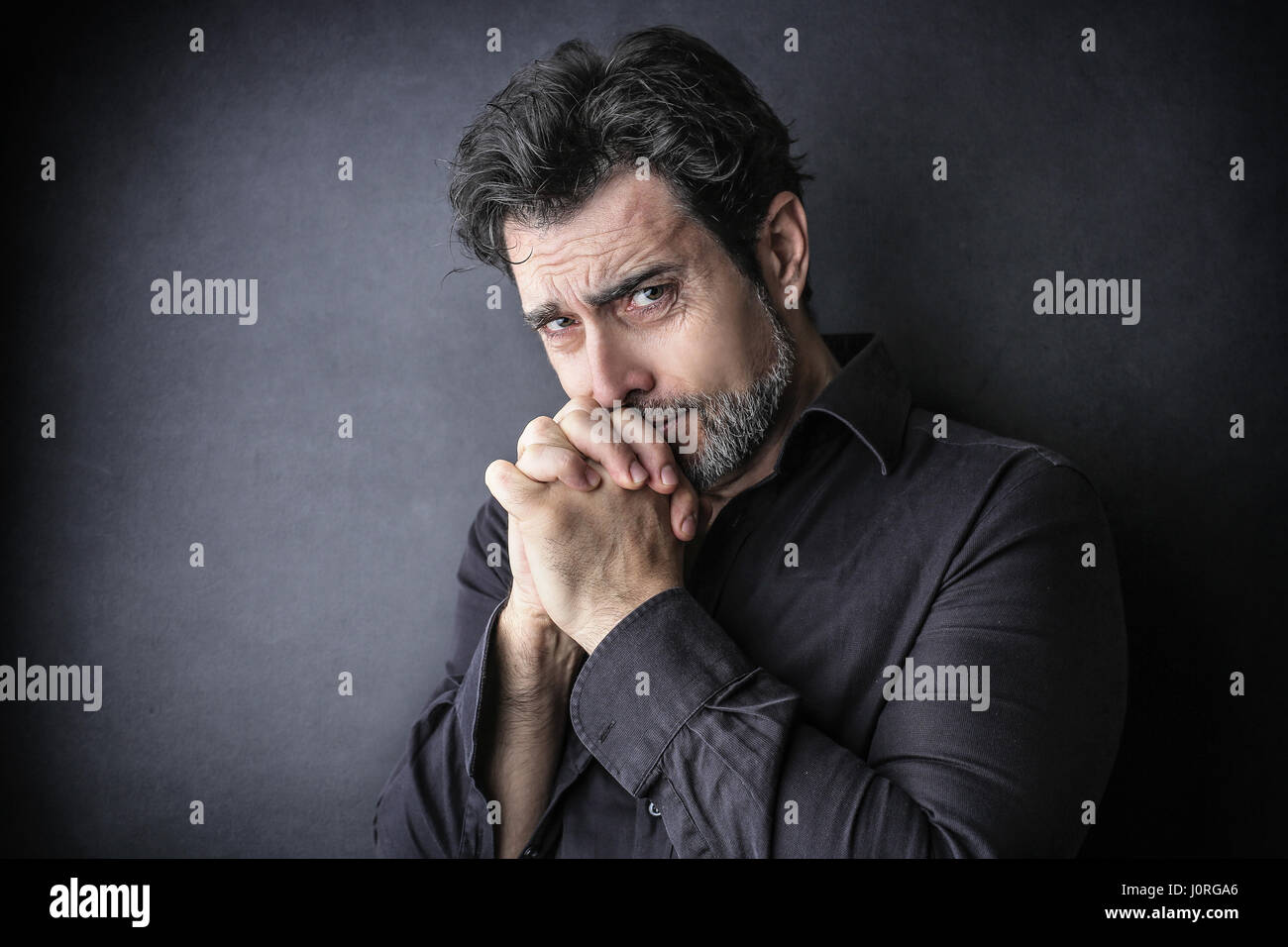 Worried man praying inside Stock Photo - Alamy