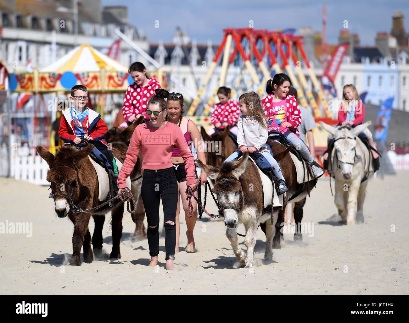 Donkey rides on Weymouth Beach, Dorset, UK. Children enjoy a donkey ...