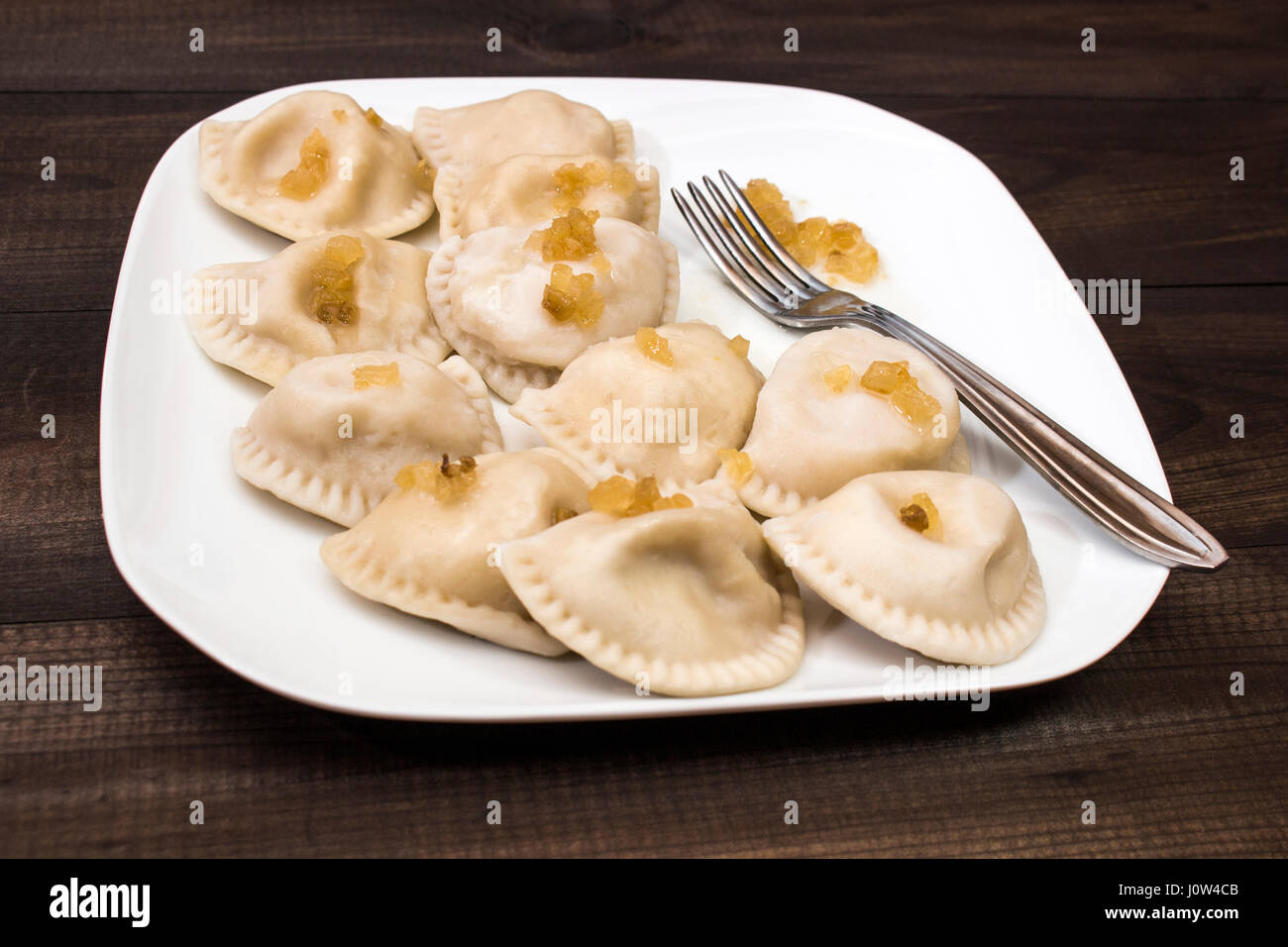 Traditional polish dumplings, "pierogi ruskie" on white plate on wooden ...