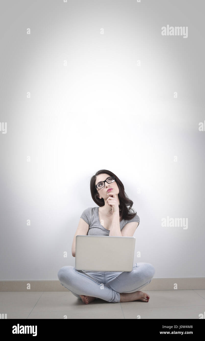 Woman with laptop thinking Stock Photo - Alamy