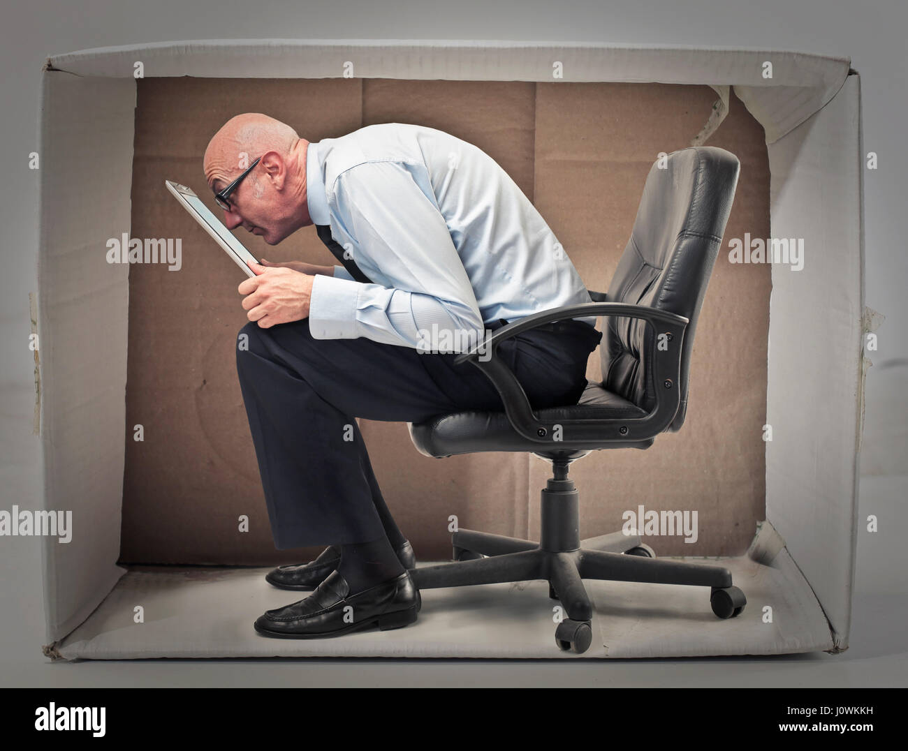 Old businessman sitting in small box Stock Photo - Alamy
