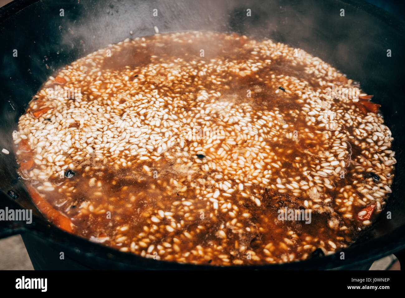 Cooking plov in the cauldron. Rice, meat, onions and carrots in a ...