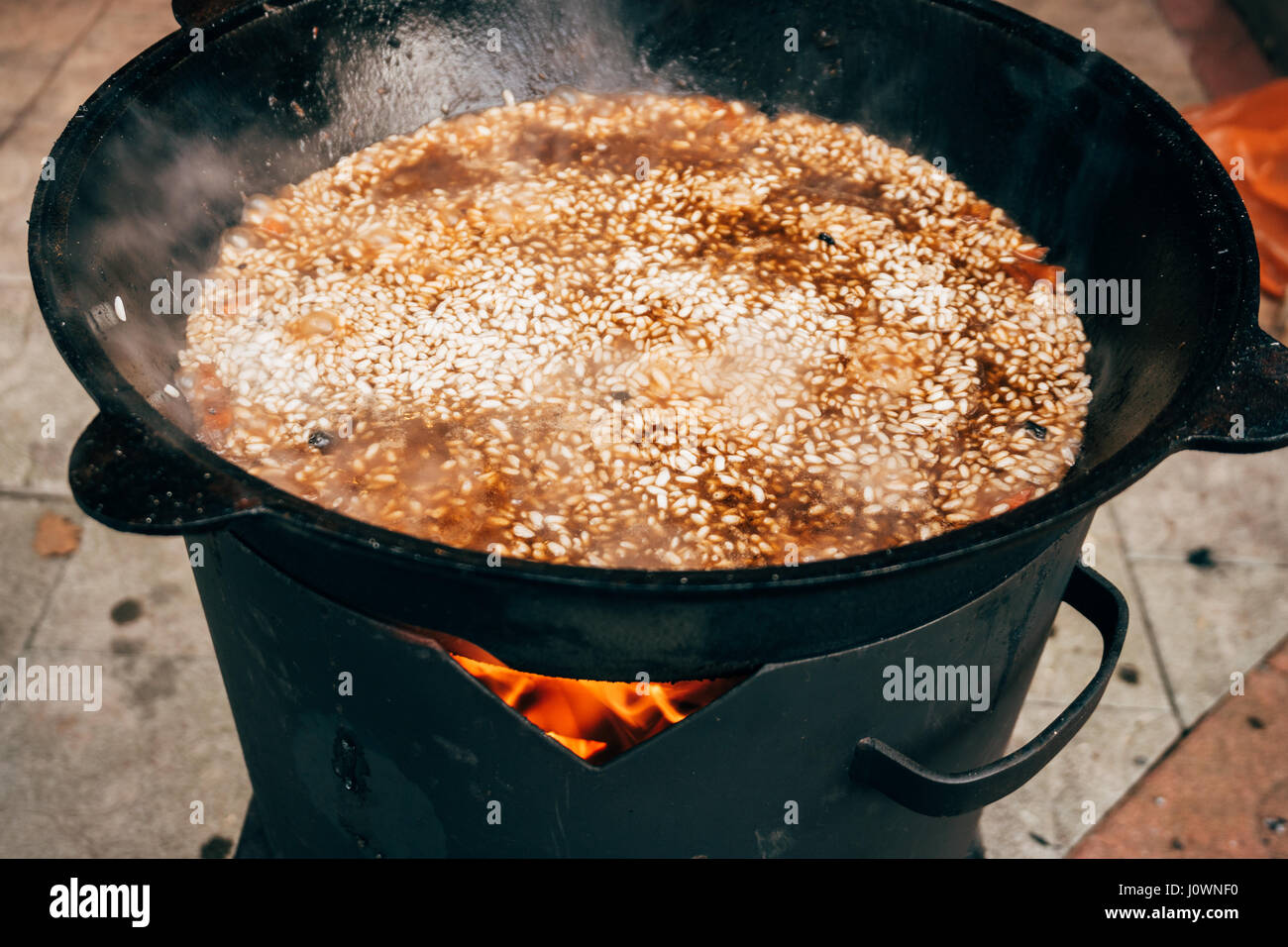 Cooking plov in the cauldron. Rice, meat, onions and carrots in a ...