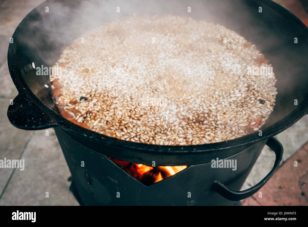 Cooking plov in the cauldron. Rice, meat, onions and carrots in a ...