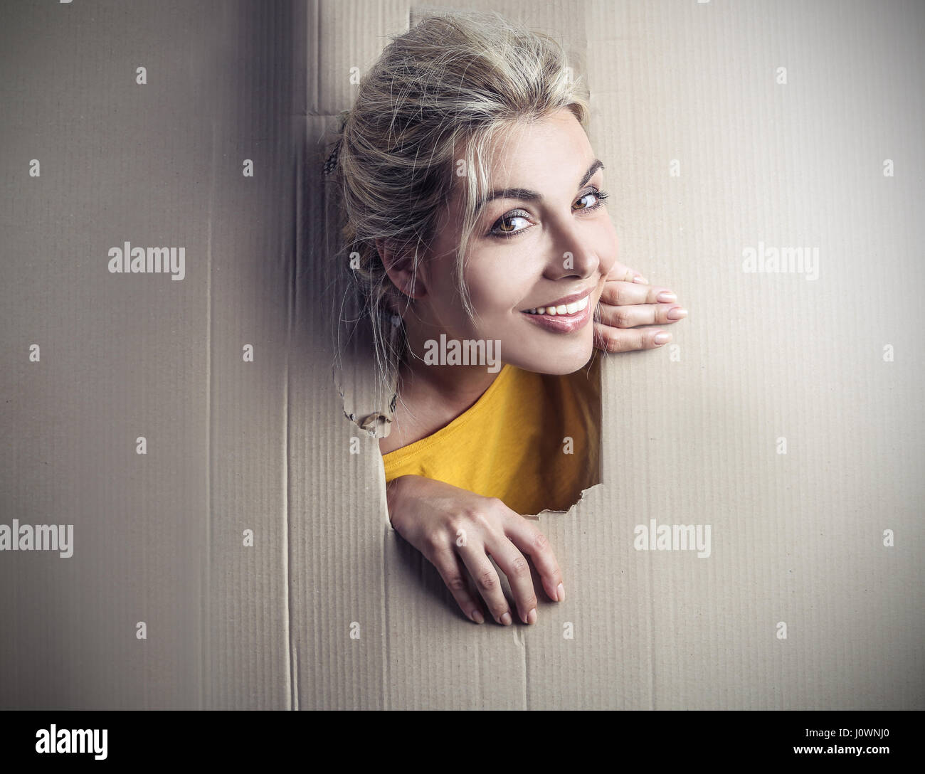 Blond woman breaking through paper Stock Photo - Alamy