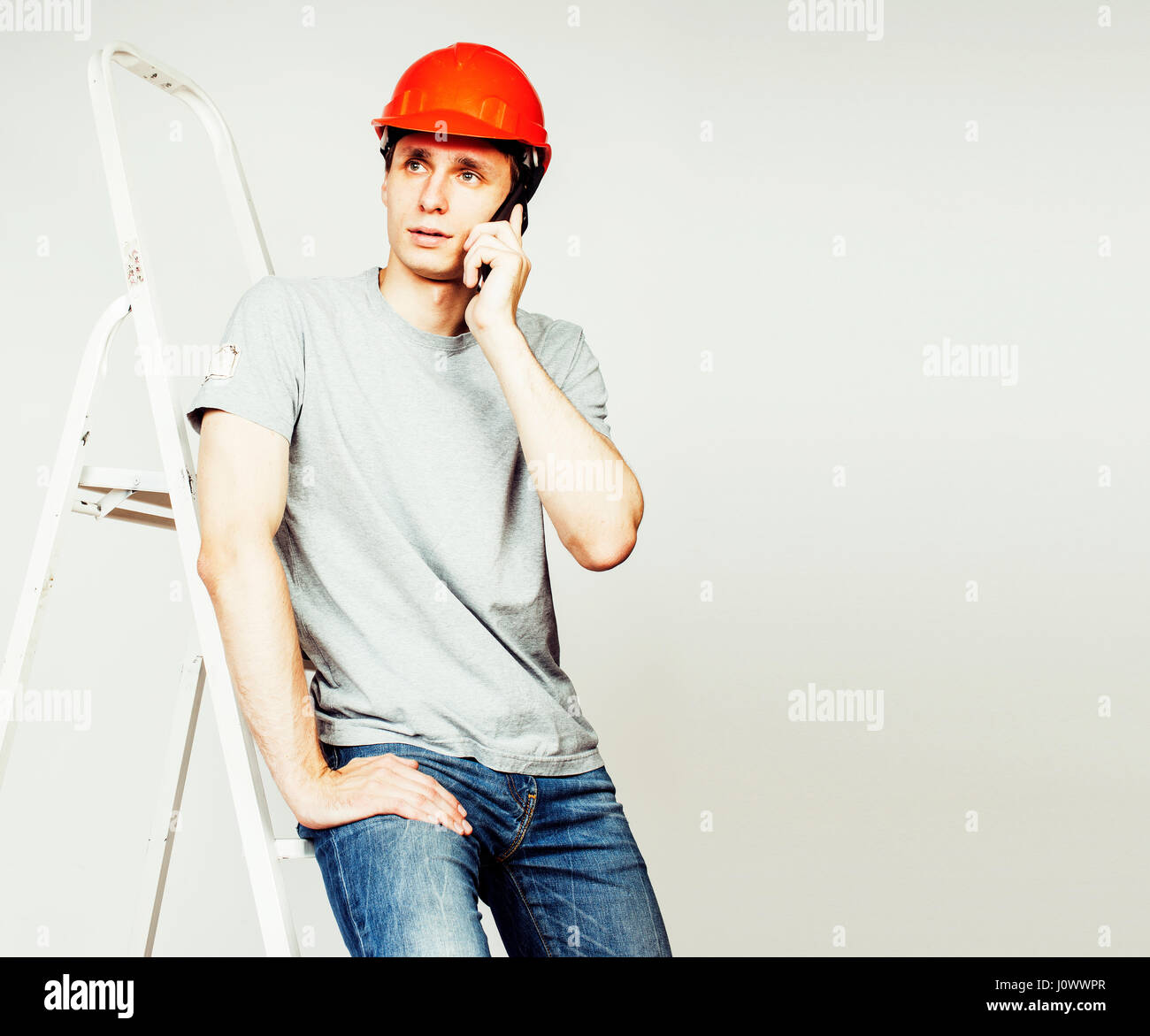 young real hard worker man isolated on white background on ladder ...