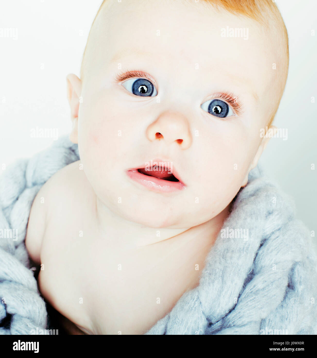 little cute red head baby in scarf all over him close up isolated ...