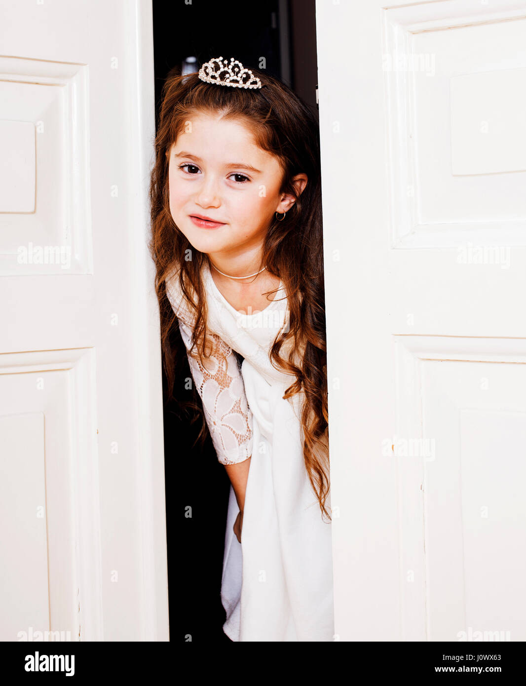 little cute girl at home, opening door well-dressed in white dress and ...
