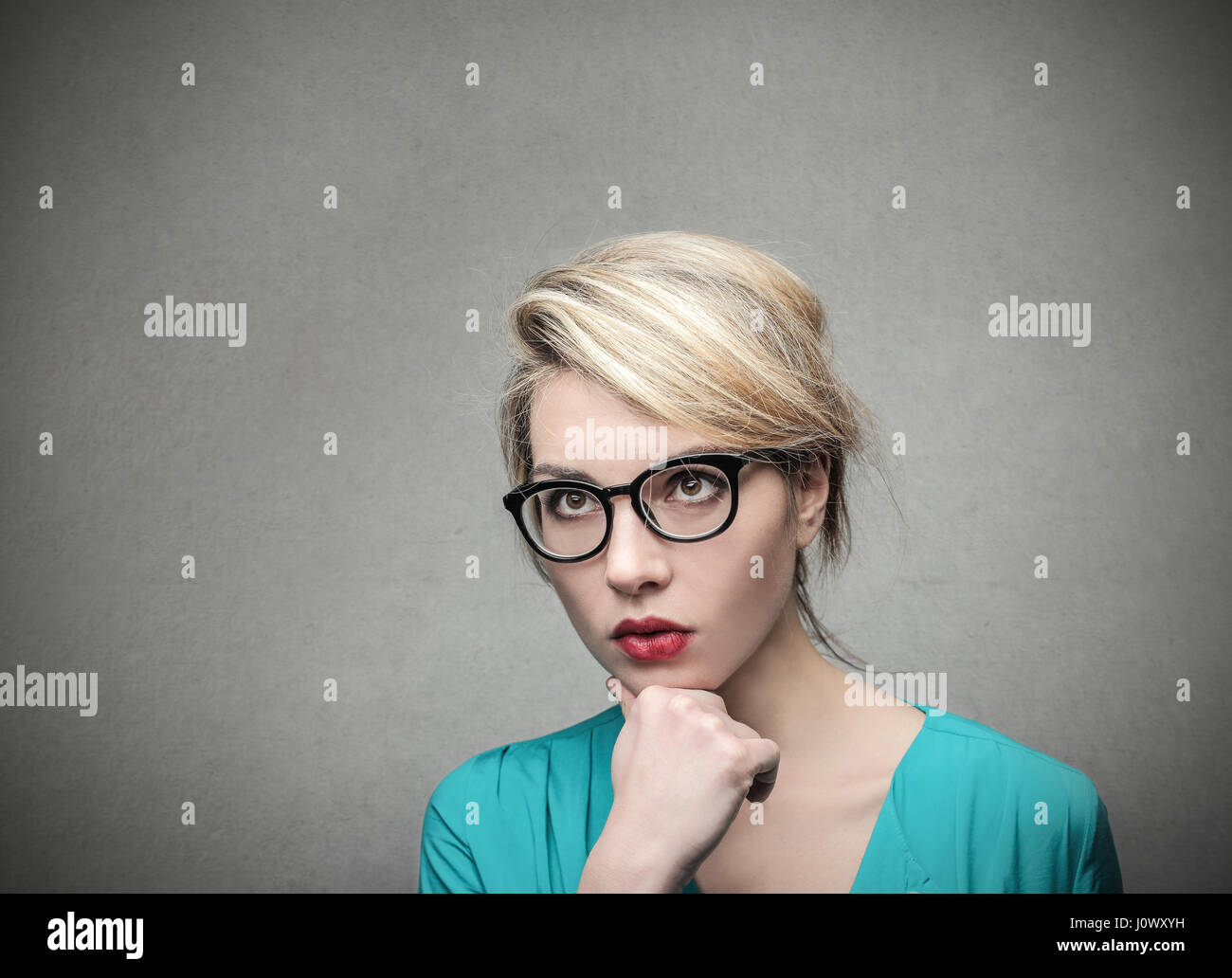 Blond woman in glasses thinking Stock Photo - Alamy