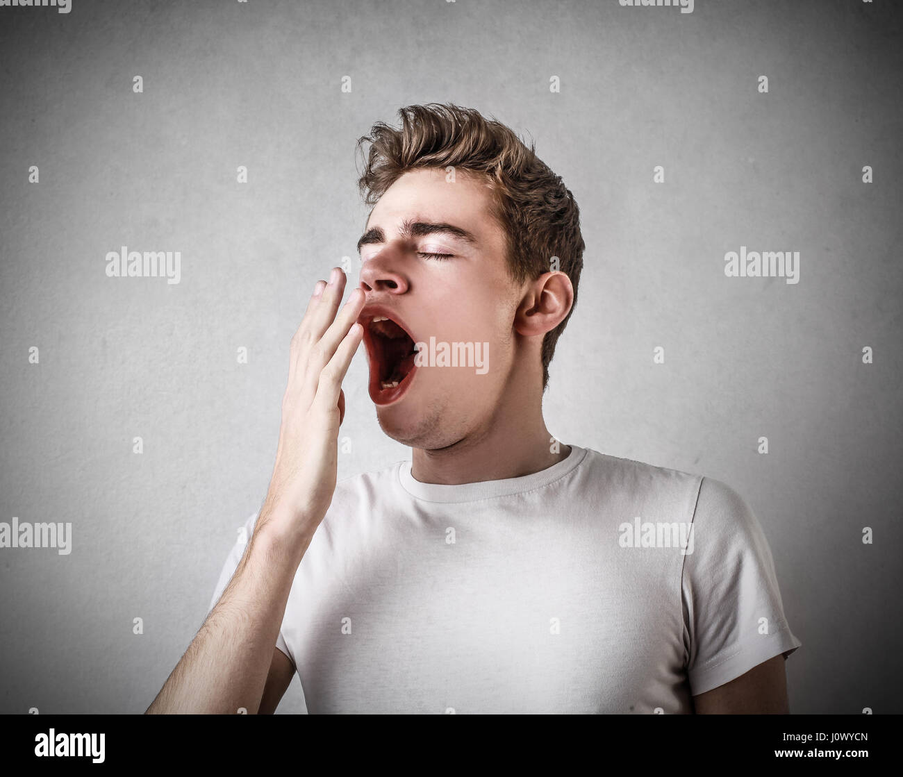 Young man yawning Stock Photo - Alamy