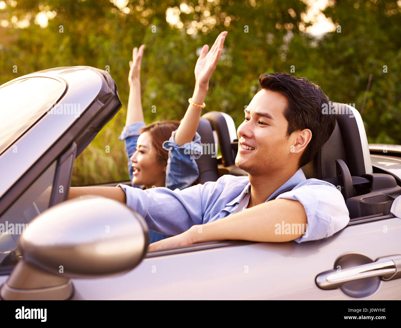 young asian couple riding in a convertible sport car at sunset Stock ...