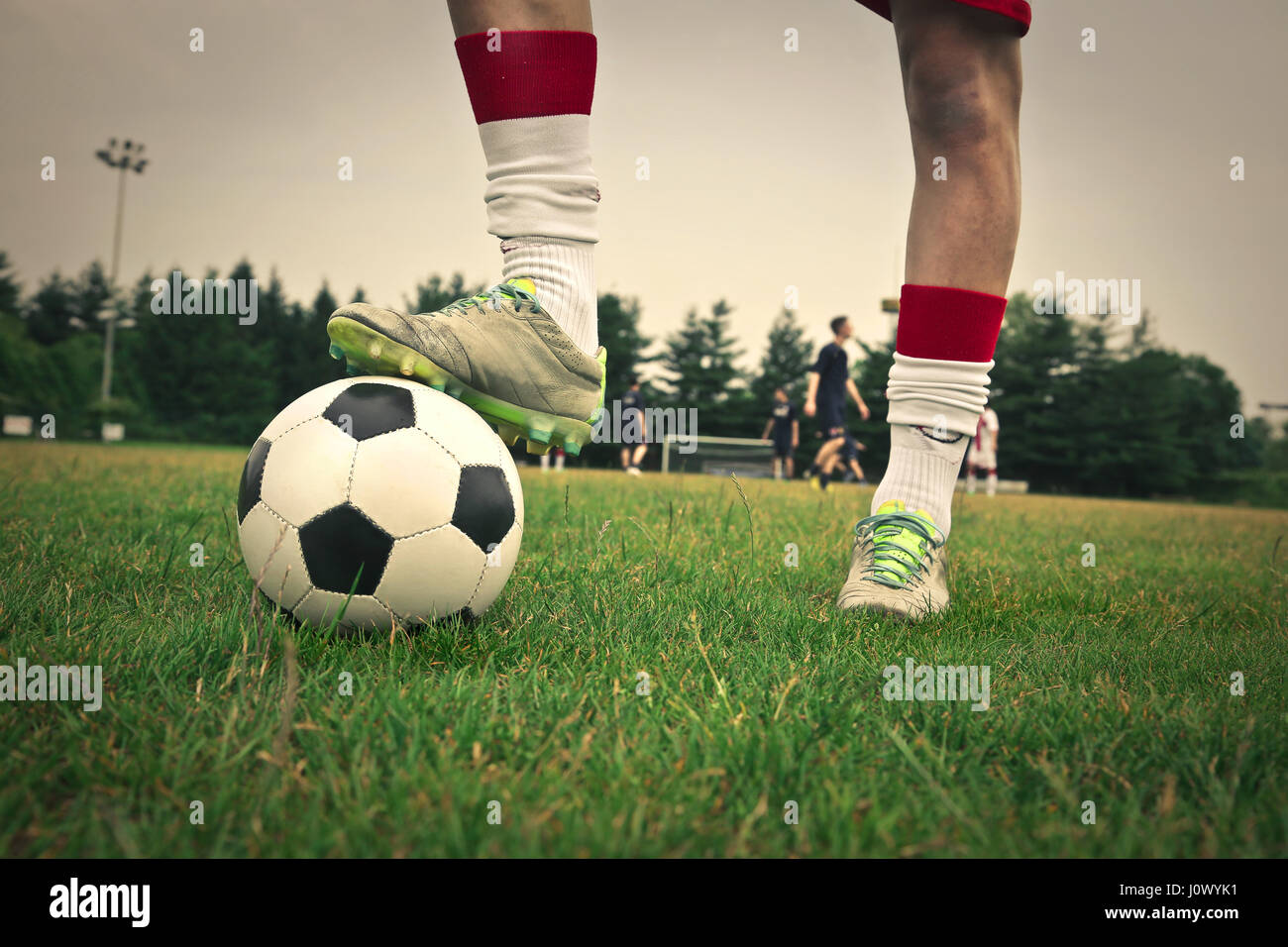 Man standing on soccer ball Stock Photo - Alamy