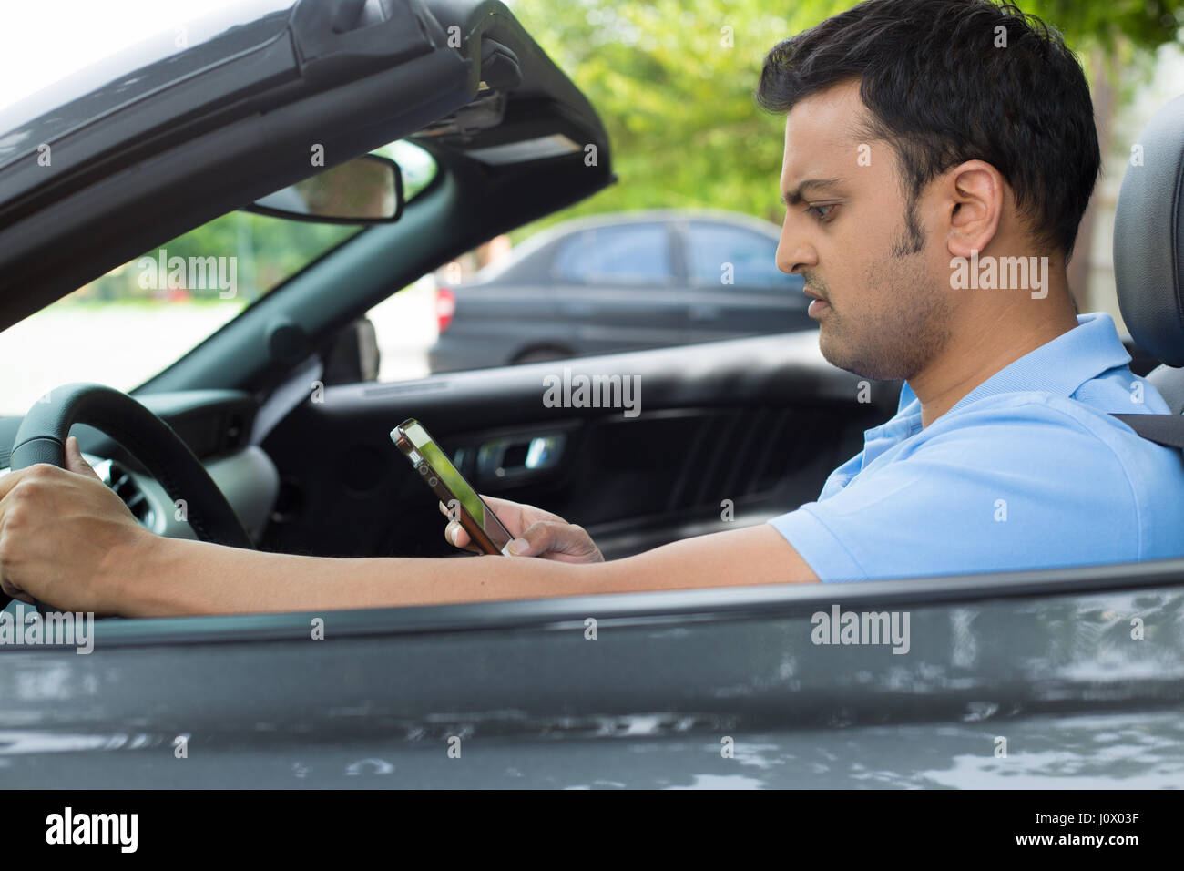 Closeup portrait, young man driving in black gray sports car and ...