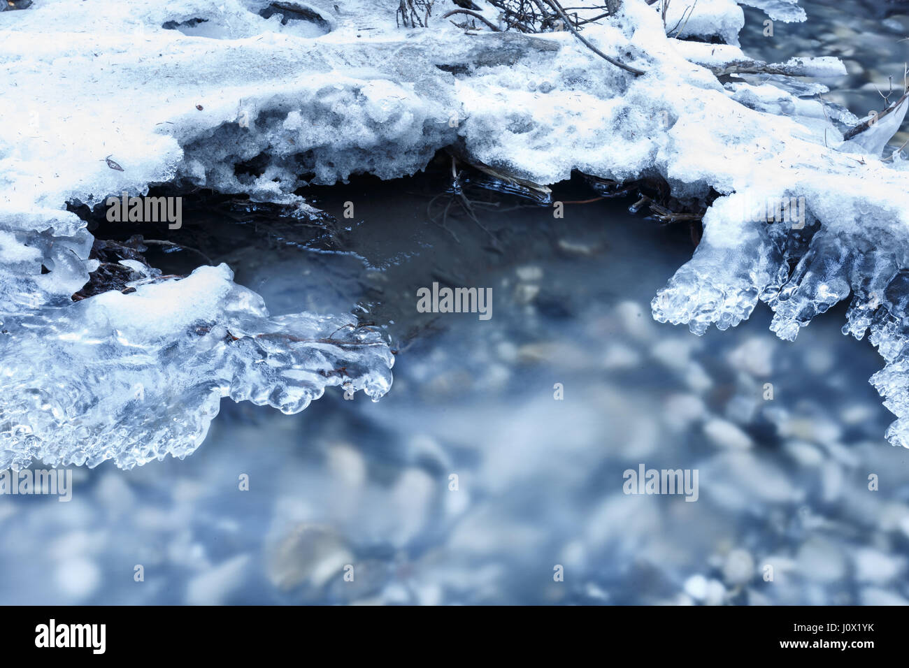 Ice lines the stream flowing Stock Photo - Alamy
