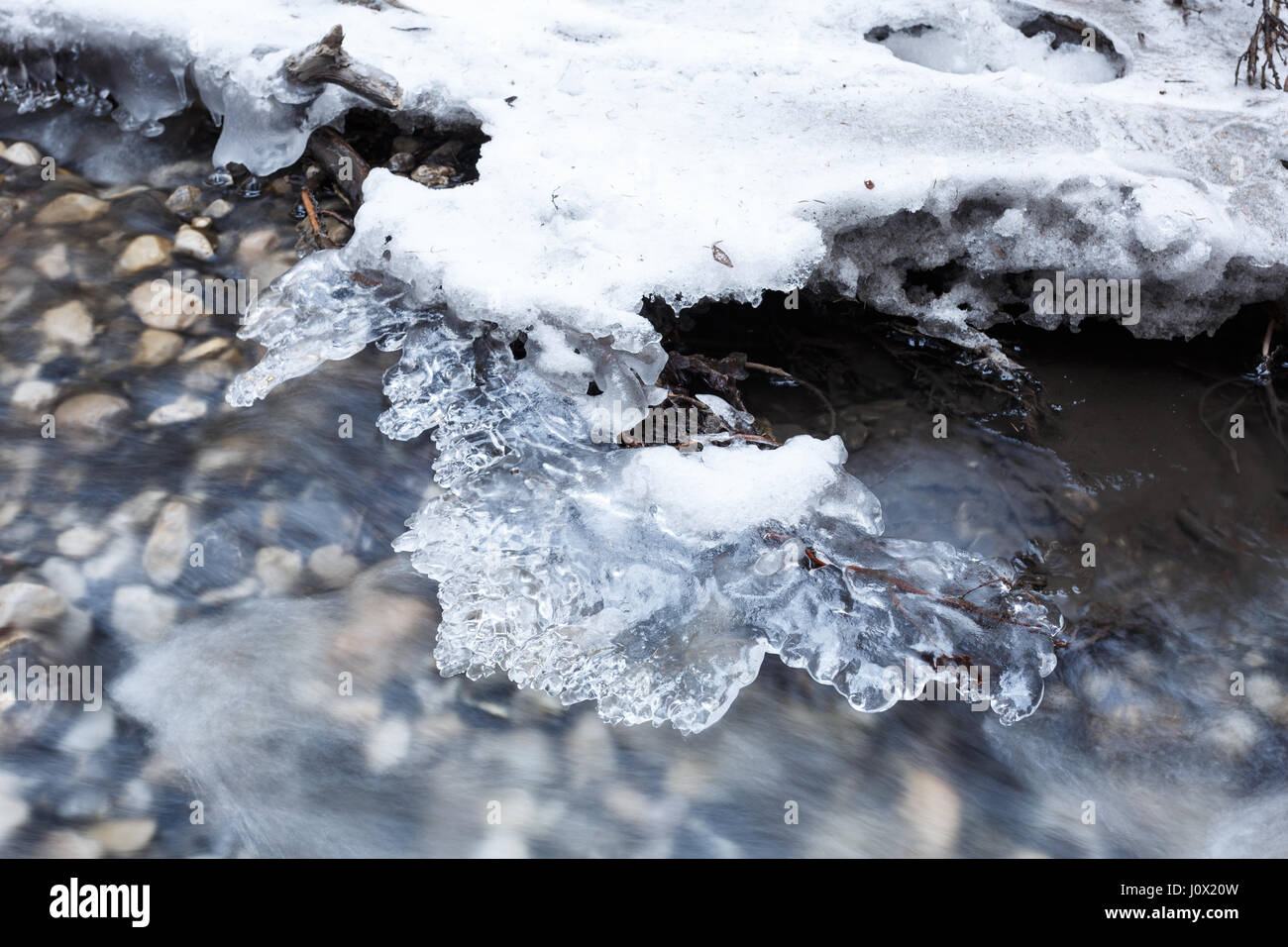 Ice lines the stream flowing Stock Photo - Alamy