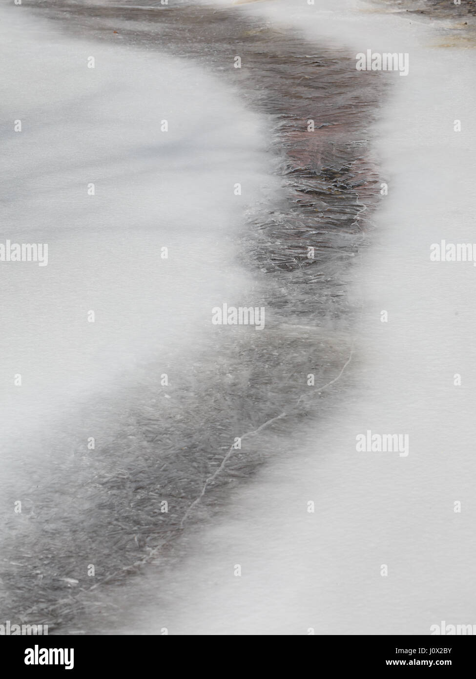 Ice lines the stream flowing Stock Photo - Alamy