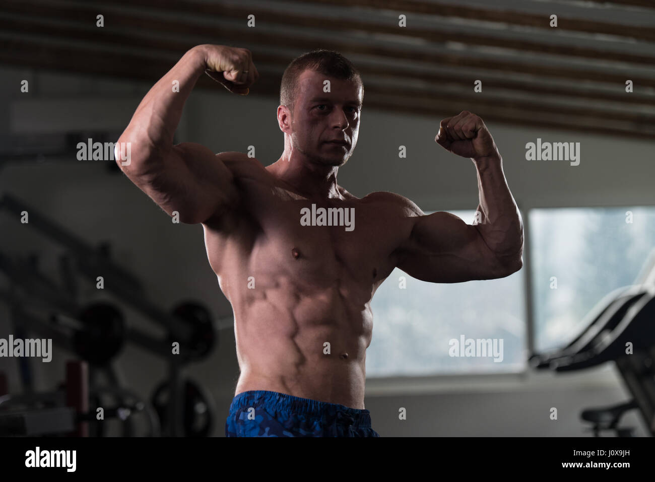 Handsome Man Standing Strong In The Gym And Flexing Muscles - Muscular ...